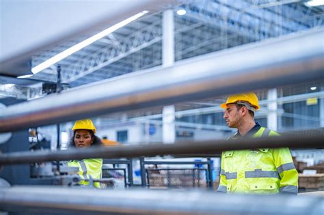 남성과 여성 기술공 엔지니어는 무거운 기계에 과정을 검사합니다 기계 공학 팀 생산 산업 제조 태블릿과 폴드를 들고 있는 작업자 첨단 기술 생산 강철에 대한 스톡 사진 및