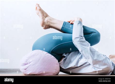 Woman Doing Yin Yoga Passive Hip Stretch Exercises On Bolster Stock