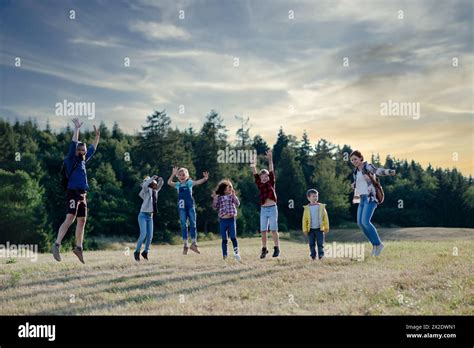 Students And Teachers Jumping On Meadow During Biology Field Teaching