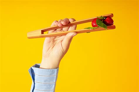 여성의 손은 노란색 바탕에 나무 집게가 달린 딸기와 샐러드를 들고 있다 과일에 대한 스톡 사진 및 기타 이미지 과일 노랑
