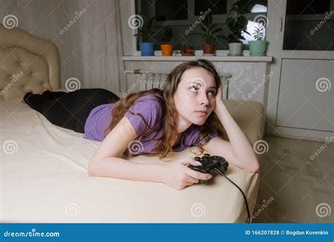 Girl Gamer Plays With A Gamepad While Looking At The Screen In Front Of