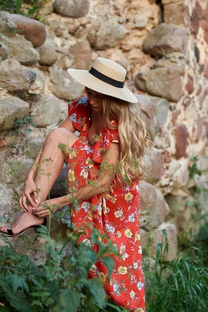 Premium Photo Beautiful Blonde In A Summer Dress And A Straw Hat Buttons Up Her Shoes