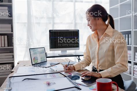 젊은 아시아 여성 사업가 관리자 변호사 또는 회사 직원이 재무 데이터를 확인하는 회계 부기 문서 또는 노트북으로 사무실에서
