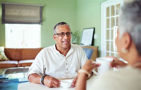 커피를 마시고 휴식을 취하고 아침에 집에서 함께 식탁에 앉아 이야기를 나누는 시니어 커플 행복하고 미소 짓는 노인 남녀가 집에서