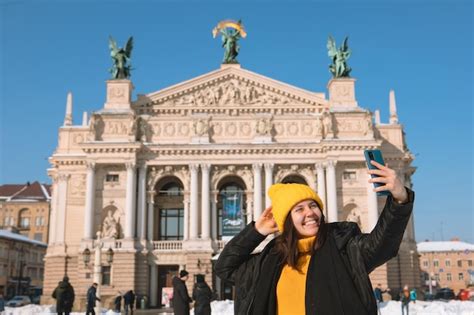 Mujer sonriente tomando selfie frente al edificio de la ópera Foto