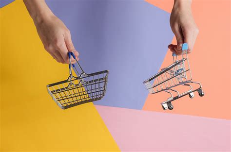 쇼핑 개념입니다 여성의 손은 색깔배경에 미니 쇼핑 바구니와 트롤리를 보유하고 있습니다 Minimalism 개념에 대한 스톡 사진