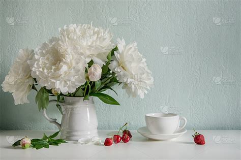 瓷瓶里放着白花牡丹桌上放着茶和浆果