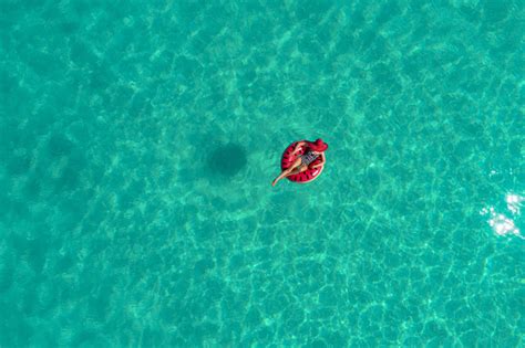 세이셸의 투명한 청록색 바다에서 수영 링 도넛에서 수영하는 슬림 한 여성의 공중 보기 소녀와 여름 바다 풍경 아름다운 파도 다채로운 물 드론에서 보기 바다에 대한 스톡 사진