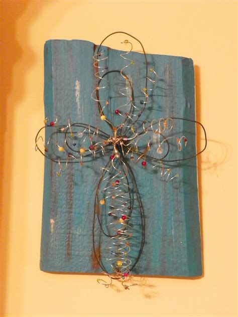 A Piece Of Art That Looks Like A Cross Made Out Of Wire And Glass Beads
