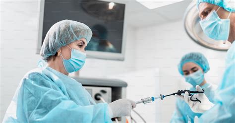 외과 수술 중 의사를 돕는 멸균 장갑을 낀 여성 미친 노동자의 측면 모습 그들은 투관침으로 복강경 그래퍼를 들고 있습니다 사진 Unsplash의 실내 이미지