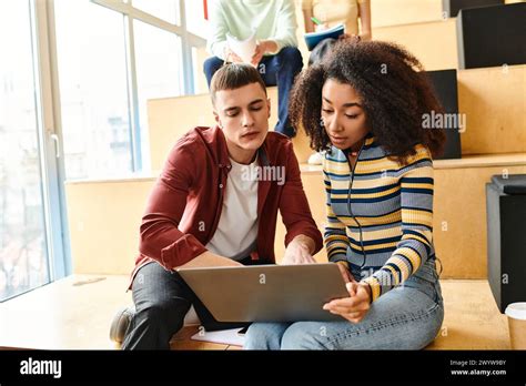 A Black Girl And A Man Sit On The Floor Focused On A Laptop Screen
