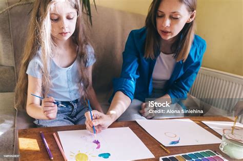 어머니와 딸이 그림을 그립니다 미술 교사는 수채화 물감 구 아슈를 적용하는 기술을 가르치고 브러시를 올바르게 잡는 방법을 가르칩니다 행복한 어린 시절 개념입니다 웃는 사람들