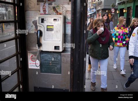 People Passing A Public Telephone Box Which Has Sex Cards Tacked Up