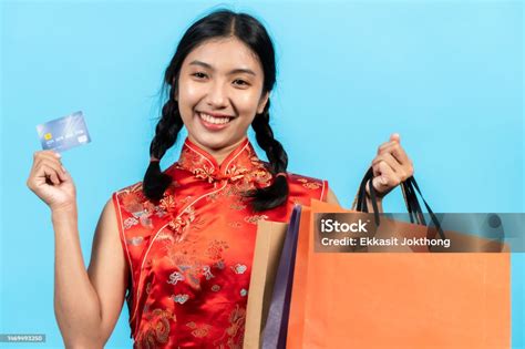 중국 설날에 치파오를 입은 소녀는 쇼핑 후 손에 신용 카드와 많은 종이 봉지를 보여주고 그의 얼굴은 행복해 보였습니다 파란색