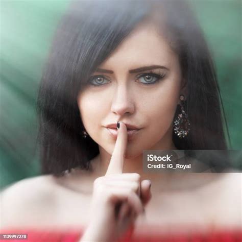 어두운 긴 머리를 가진 젊은 여자는 입술에 집게 손가락으로 쉿 침묵 제스처 갈색 머리에 대한 스톡 사진 및 기타 이미지 갈색 머리 검은색 공포 무서움 Istock