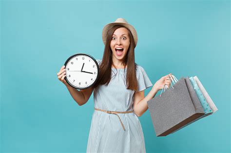 초상화 아름 다운 여름 드레스 밀 짚 모자 지주에 젊은 백인 여자 쇼핑 블루 파스텔 배경에 고립 시계 라운드 후 구매 가방
