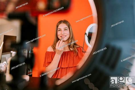 Smiling Female Vlogger Applying Lipstick While Filming At Home Stock