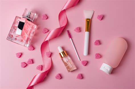 핑크 배경에 종이 쇼핑백이있는 플라스틱 용기에 스킨 케어 에센스 유리 병 퍼퓸 바디 로션 노화 방지 세럼 콜라겐 및 펩타이드 한방울을 곁들인 병 화장품 가방에 대한 스톡