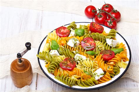 이탈리아 요리화려한 파스타 체리 토마토 Feta 치즈와 흰색 나무 바탕에 신선한 바 질 샐러드 건강한 식생활에 대한 스톡 사진