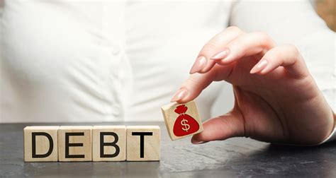 손은 달러 이미지와 단어 부채와 나무 블록을 둔다 국가에 대 한 세금 및 채무 지불 금융 위기와 문제의 개념 채무 면제 대출 리스크 관리 지불금 가계에 대한 스톡 사진 및