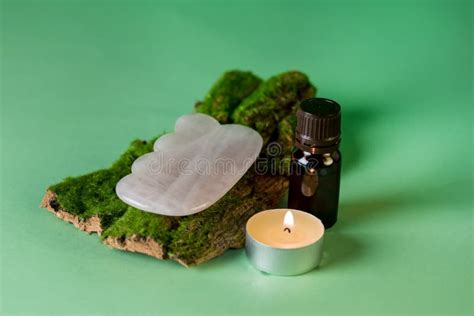 Glass Bottle With Oii Gua Sha Stone For Face Massage On Tree Bark On