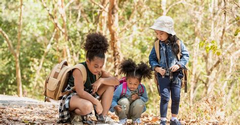 다양성의 그룹 여름 화창한 날에 숲 산에서 함께 배낭 하이킹을 하는 어린 소녀 친구들 세 아이가 앉아서 숲을 탐험하는 지도를 보며 즐거운 야외 활동을 하고 있습니다 사진