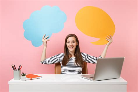 행복 한 여자 파스텔 핑크 배경에 고립 된 Pc 노트북과 흰색 책상에서 파란색 노란색 빈 빈 말 클라우드 연설 거품 일을 개최 성과 비즈니스 경력 개념입니다 광고에 대 한