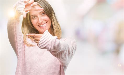 손으로 만드는 프레임 및 행복 한 얼굴로 손가락을 웃 고 고립 된 배경 위에 겨울 스웨터를 입고 젊은 아름 다운 여자 창의력과 사진 개념입니다 가을에 대한 스톡 사진 및