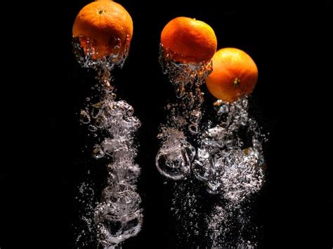 Mandarinas Cayendo Al Agua Con Salpicaduras Sobre Fondo Negro Foto