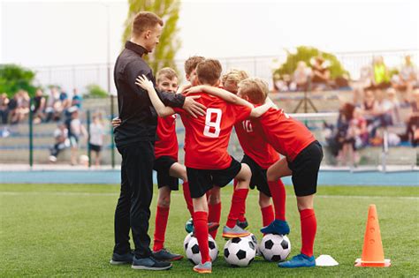 코치가 원 안에 서 있는 행복한 축구 아이들 토너먼트 경기 휴식 시간 동안 트레이너와 함께 모이는 축구 팀의 아이들 아이에 대한