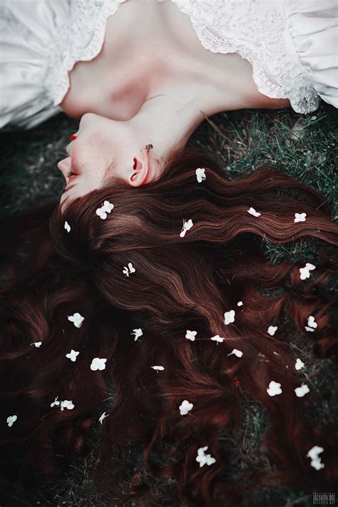 Фото Девушка лежит на траве с распущенными волосами с белыми цветочками на них фотограф