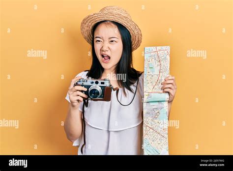 Young Chinese Girl Holding City Map And Vintage Camera Angry And Mad