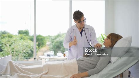백인 의사의 초상화는 요양원이나 클리닉에서 의료 및 건강 관리 치료를 위해 병원의 침대에서 아픈 환자의 시체를 확인합니다