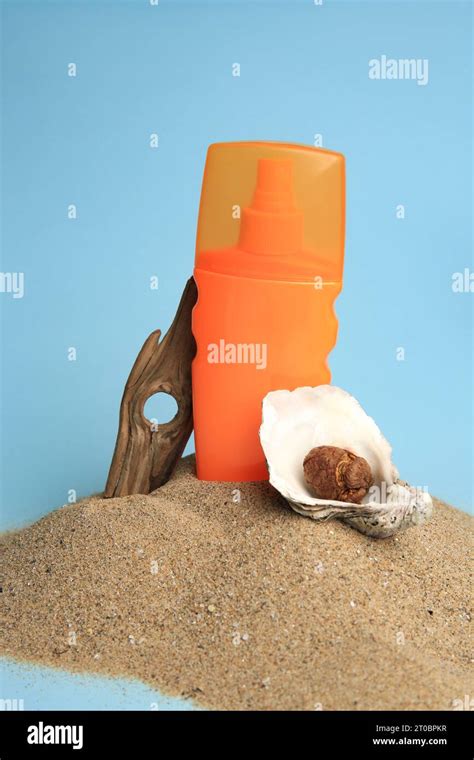 Sand With Bottle Of Sunscreen Tree Bark And Seashells Against Light Blue Background Sun