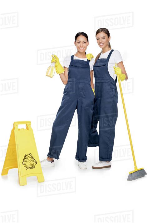 Multiethnic Smiling Cleaners In Uniforms With Broom And Detergent Isolated On White Royalty