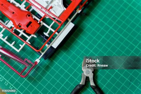 A Sharp Plier On Green Cutting Mat With Finished Plastic Model Runner