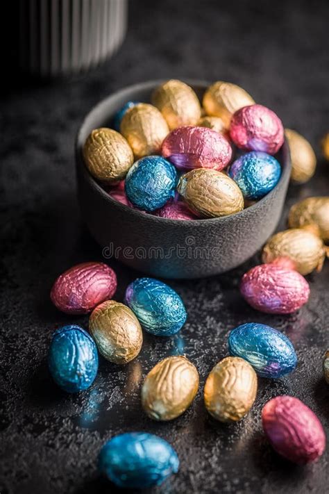 Chocolate Easter Eggs Wrapped In Multi Colored Foil In Bowl On Black
