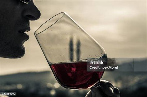 흐릿한 배경에서 더러운 와인 글라스와 함께 레드 와인을 마시는 사람 얼굴의의 근접 촬영 와인 글라스에 모스크 첨탑 실루엣입니다