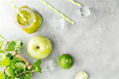 회색 바탕에 녹는 얼음 조각 라임 민트 녹색 사과와 메이슨 항아리에 그린 Healty 음료 채식 식품 개념입니다 해독 각얼음에