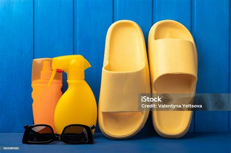 파란색 질감 배경에 해변 액세서리가 있는 플랫 레이 구성 비치 슬리퍼 선글라스 및 자외선 차단제 Spf 자외선 차단제 복사를 위한 공간입니다 텍스트를 위한 위치입니다 휴가