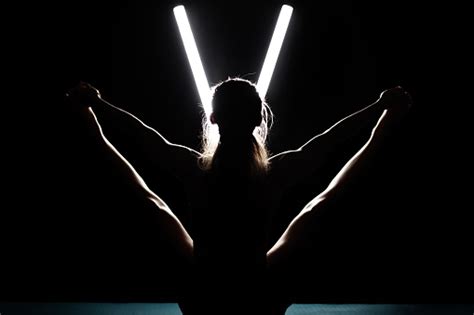 요가 포즈를 연습하는 여자에 적합합니다 실루엣 소녀는 V 모양의 흰색 Led 튜브 빛과 검은 배경에 대한 스튜디오에서 운동을하고 스트레스 내부 균형 개념이 없습니다 실루엣에