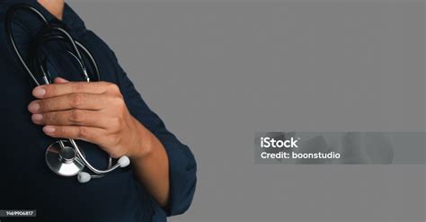 회색 배경에 서 있는 동안 청진기를 들고 있는 의사의 측면 보기 의사에 대한 스톡 사진 및 기타 이미지 의사 측면 보기 건강관리와 의술 Istock