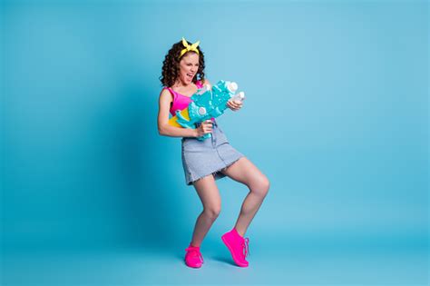 미친 쾌활한 숙녀 놀이 물 총 펌프의 전체 길이 사진 파란색 배경에 고립 된 미니 데님 스커트를 착용 갈색 머리에 대한 스톡