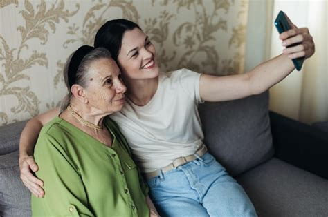Abuela y nieta miran el teléfono inteligente mientras están sentadas en
