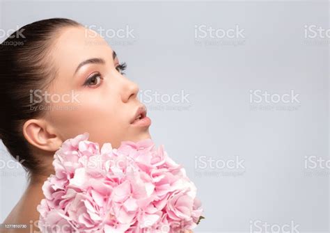 건강한 깨끗한 피부와 신선한 메이크업과 아름다운 갈색 머리 여자의 초상화 그녀는 얼굴 근처에 분홍색 수국을 안고 있다 미용 미용