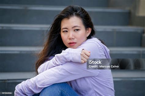 젊은 슬 프 고 우울 아시아계 미국인 학생 여자 또는 야외에서 압도 하 고 절망적 인 기분이 불안 거리 계단에 앉아 왕 따 십