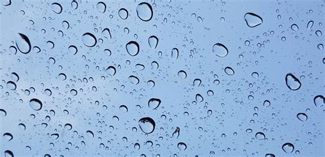 Water Droplets Perspective Through Window Glass Surface Against Blue