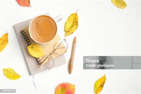 낙엽 커피 한 잔 종이 노트북 흰색 배경에 펜이있는 가을 책상 아늑한 홈 테이블 Hygge 편안한 작업 공간 가을 가을 개념