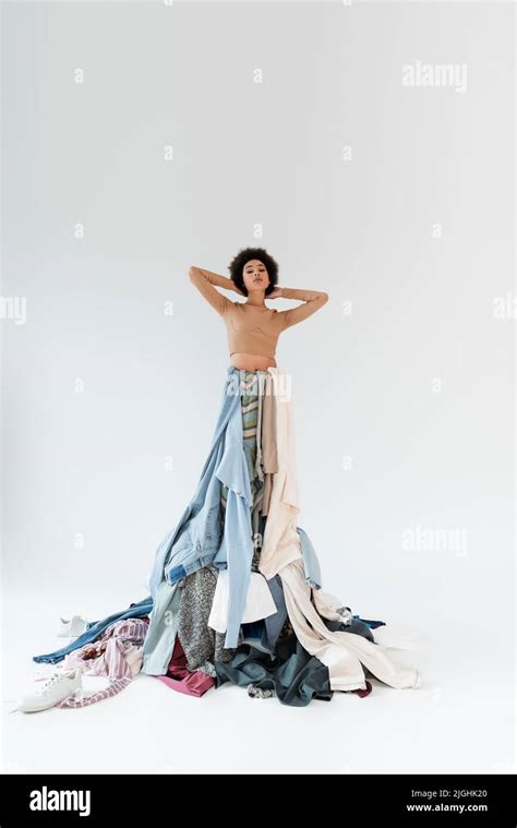 Trendy African American Woman Posing On Pile Of Clothes With Hands