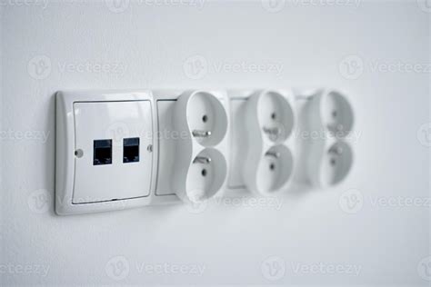 Close Up Of White Electrical Sockets And Ethernet Ports On White Wall